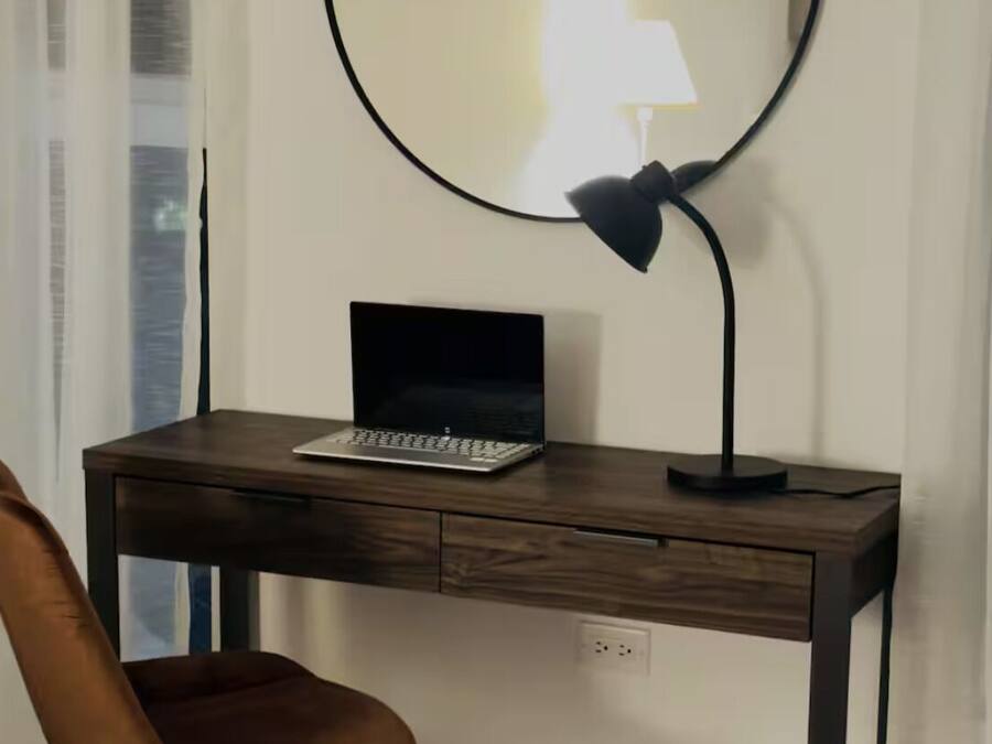 Uma mesa de madeira com um laptop e uma lâmpada de mesa.