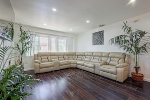 Sofá modular em sala de estar com piso de madeira e plantas em vasos.