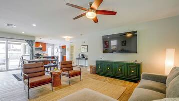 Uma sala de estar com ventilador de teto, televisão e um armário verde.