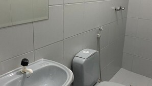Casa de banho com lavatório pedestal, sanita e espelho na parede.