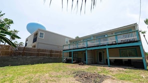Uma casa de dois andares com varanda, garagem e quintal cercado.