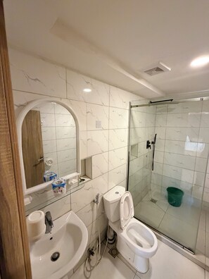 Uma casa de banho moderna com chuveiro envidraçado, lavatório e sanita.