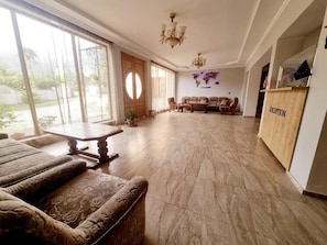 Ampla sala de estar com sofá, mesa de centro e balcão de recepção.