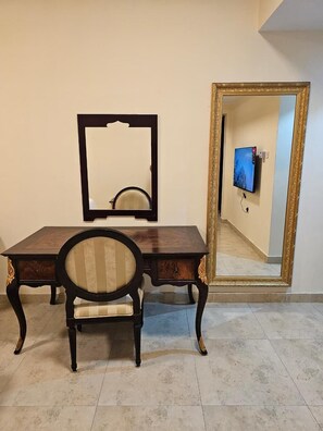 Quarto com escrivaninha de madeira, uma cadeira e espelhos, incluindo um grande na parede.