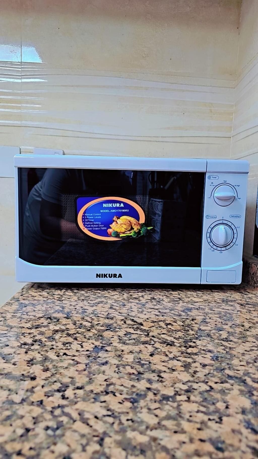 Forno de micro-ondas branco com visor digital sobre bancada de granito.