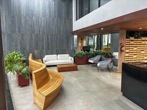 Um lobby moderno com um banco de madeira curvo, um sofá branco e uma mesa de recepção.