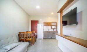 Uma cozinha moderna com micro-ondas embutido, uma mesa de jantar de madeira com cadeiras e uma TV de tela plana fixada na parede.