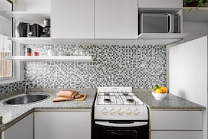 Cozinha com fogão a gás, micro-ondas e painel de azulejos.