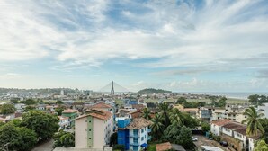 Paisagem costeira urbana com uma ponte pênsil imponente, edifícios residenciais e vista para o mar.