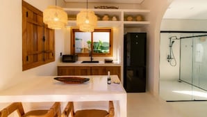 Cozinha moderna com armários de madeira, bancada branca e duas luminárias pendentes.