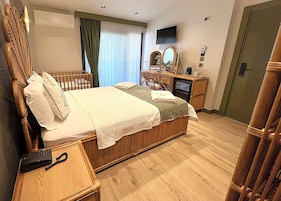 Quarto de hotel com cama, escrivaninha, cadeira, televisão e guarda-roupa.