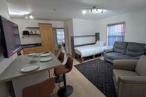 Um espaço compacto com cozinha compacta, área de jantar, cama e espaço para sentar.