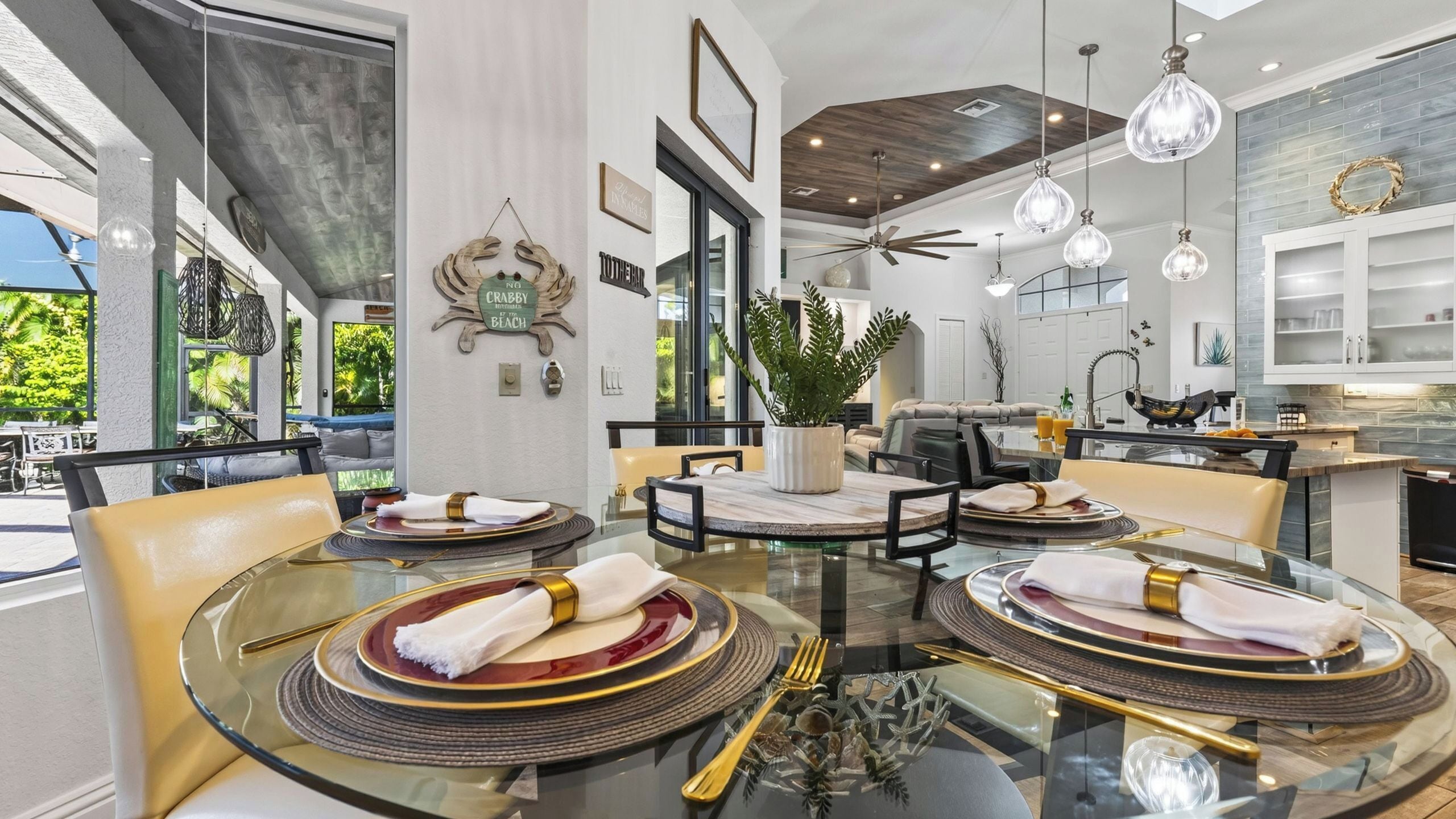Uma área de refeições moderna com uma mesa de vidro posta para quatro pessoas, cercada por cadeiras.