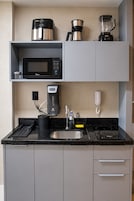 Cozinha moderna com micro-ondas, cafeteira e liquidificador na bancada.