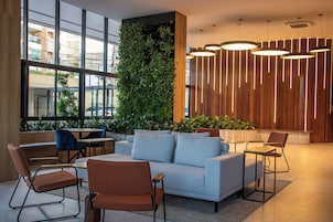 Um interior moderno com sofá, cadeiras, jardim vertical e iluminação pendente.