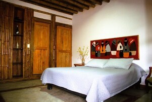 Quarto com cama grande, armário de madeira e pintura pendurada na parede.