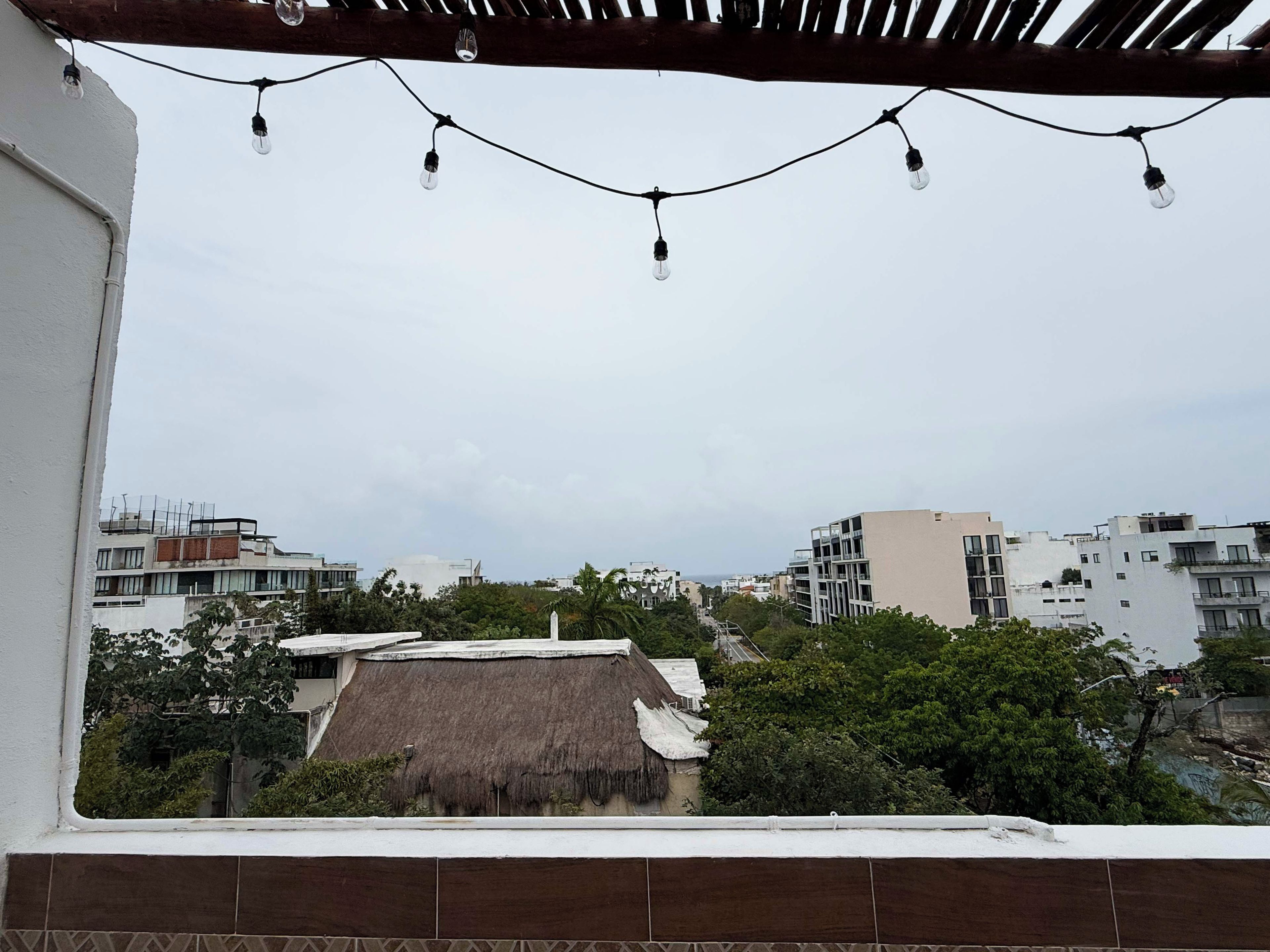 Vista de varanda com luzes de fada, mostrando uma paisagem urbana com edifícios modernos e tradicionais.