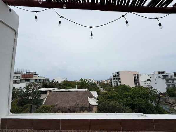 Vista de varanda com luzes de fada, mostrando uma paisagem urbana com edifícios modernos e tradicionais.