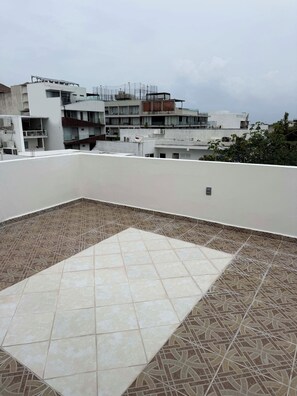 Terraço no telhado com ladrilhos estampados, rodeado por edifícios.