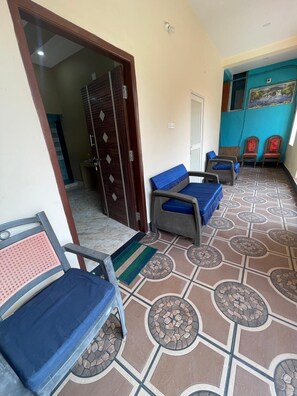 Um quarto com chão estampado, uma porta e duas cadeiras de vime com almofadas azuis.