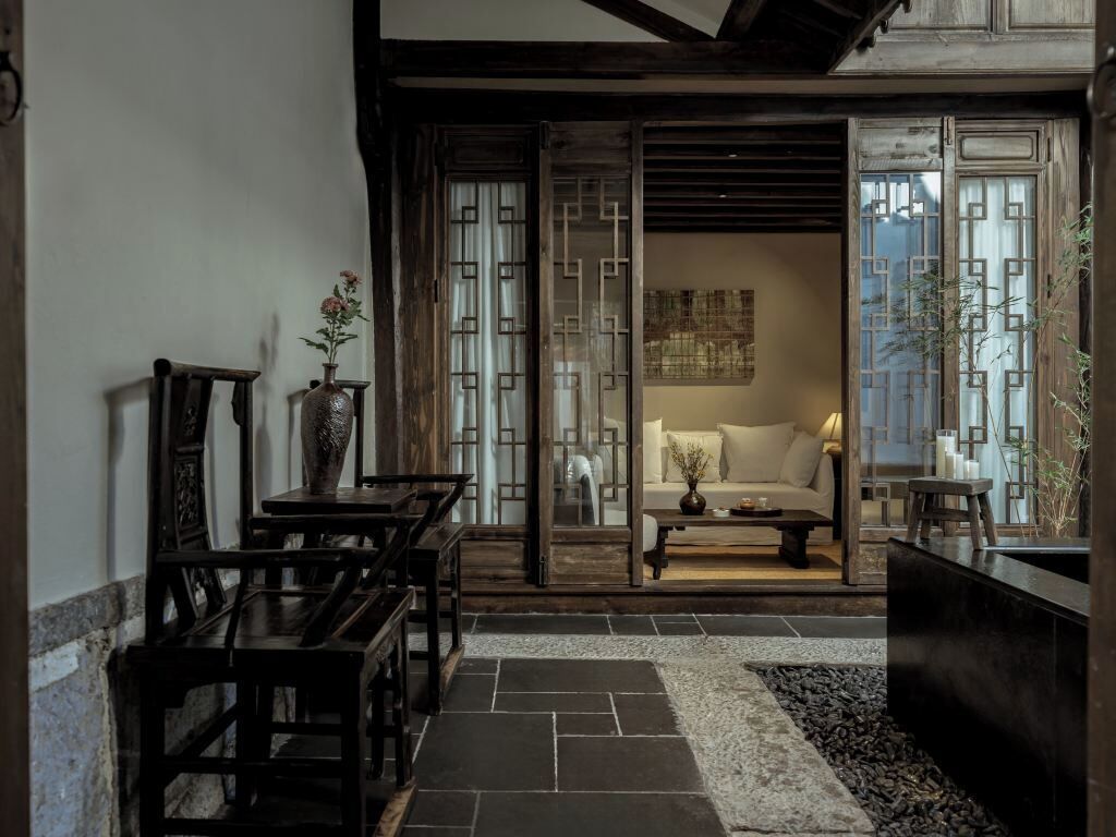 Um interior tradicional com sofá, móveis de madeira e piso de pedra.