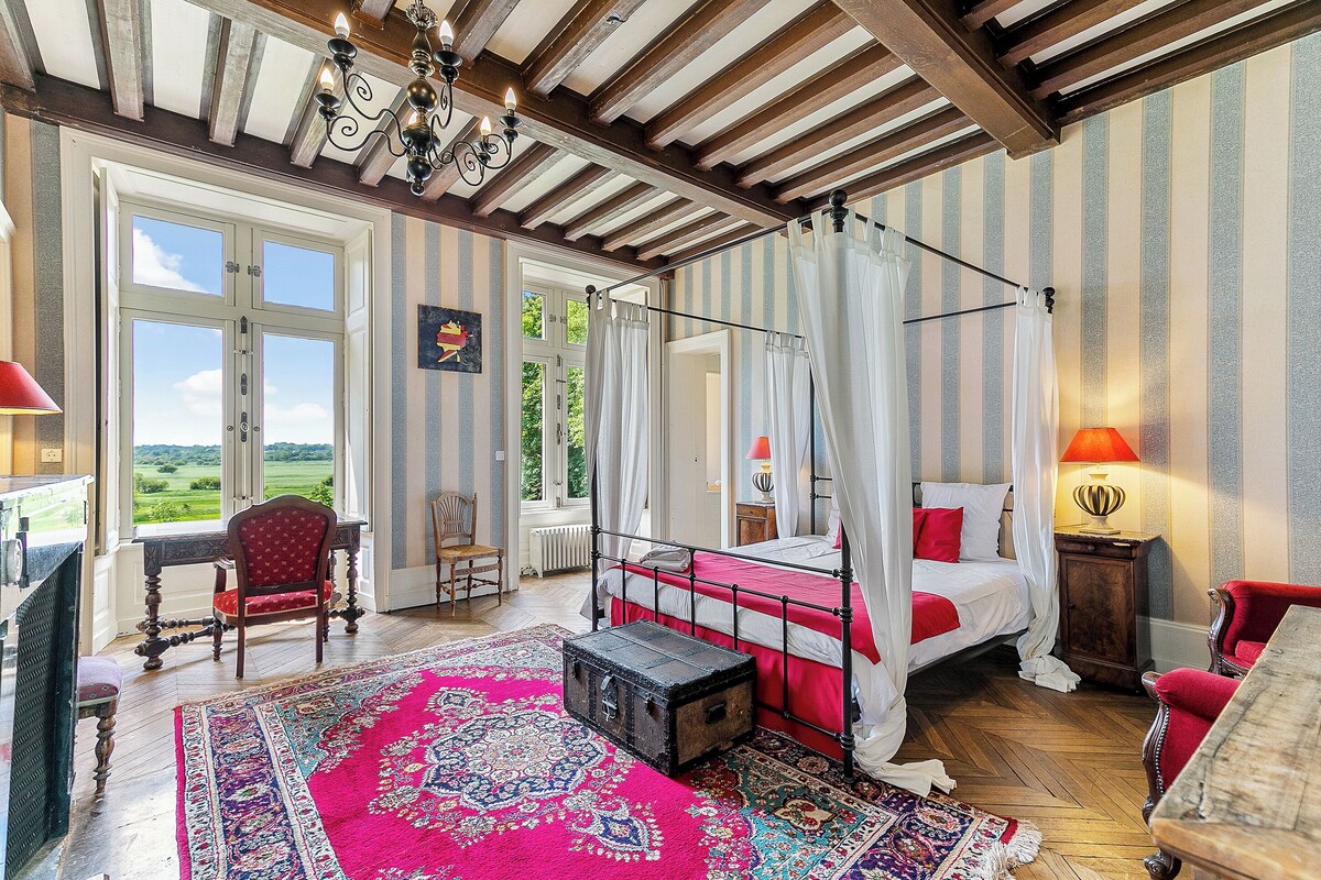 Quarto com cama de dossel, uma grande janela e vista para o exterior.