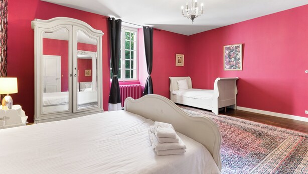 Quarto com uma cama grande, um guarda-roupa, uma cadeira e um radiador.