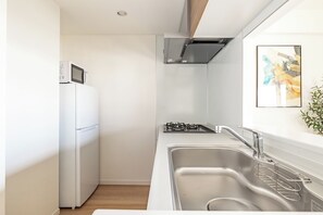Cozinha moderna com eletrodomésticos brancos, uma pia de aço inoxidável e fogão a gás.