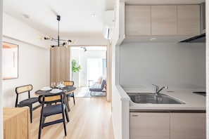 Cozinha moderna com pia, armários e área de jantar com mesa e cadeiras.