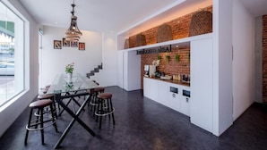 Cozinha moderna com mesa de jantar de vidro, banquetas de bar e parede decorada com tijolos.