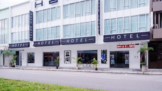 Um hotel com vários andares, fachada moderna, janelas grandes e uma placa indicando que é um hotel.