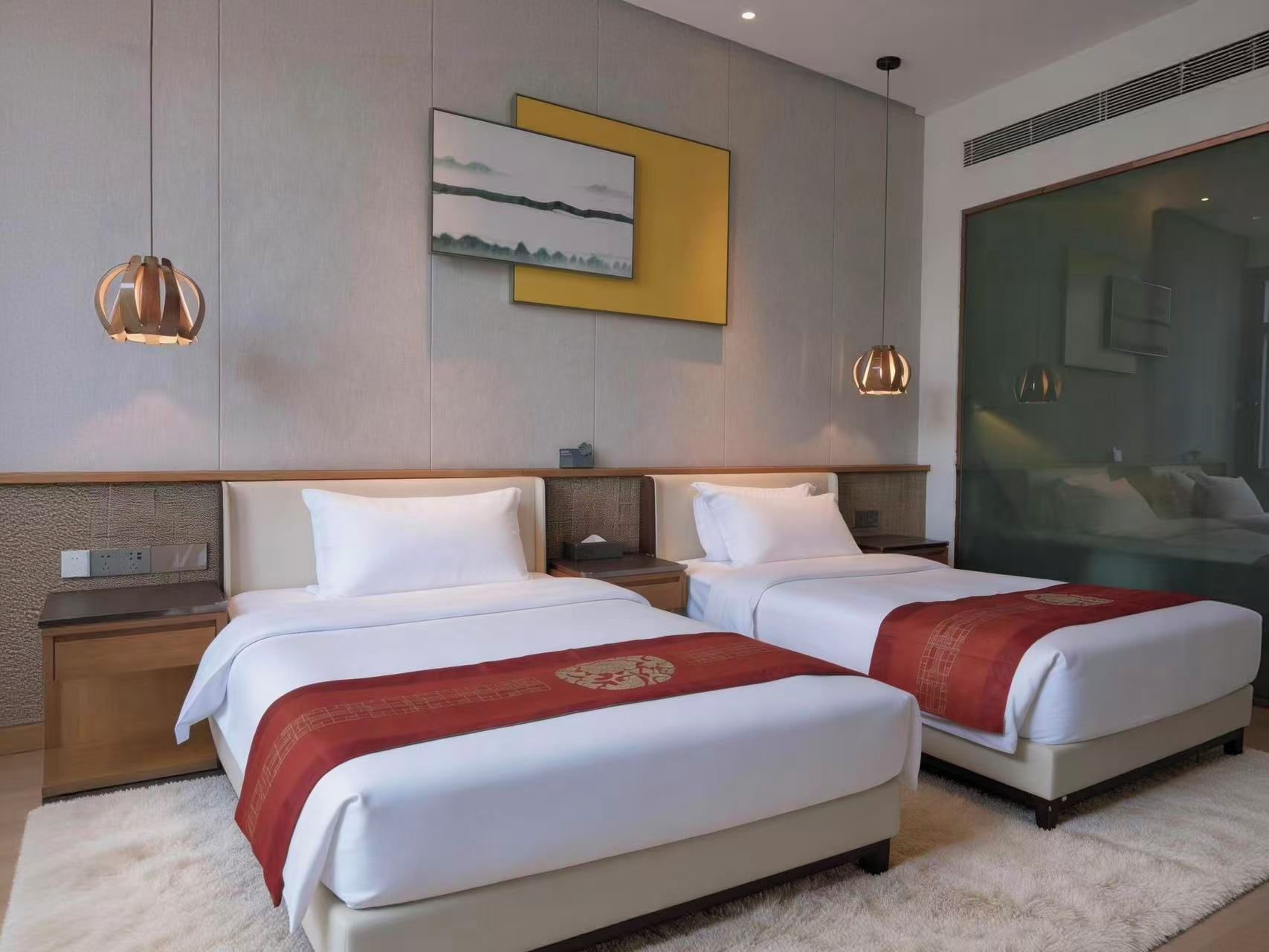 Quarto de hotel com duas camas, uma janela grande e um quadro na parede.