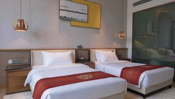 Quarto de hotel com duas camas, uma janela grande e um quadro na parede.