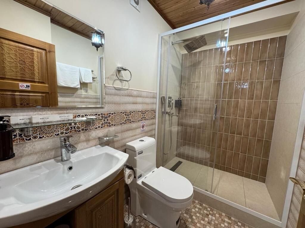 Casa de banho com lavatório, sanita e cabine de duche com vidro.