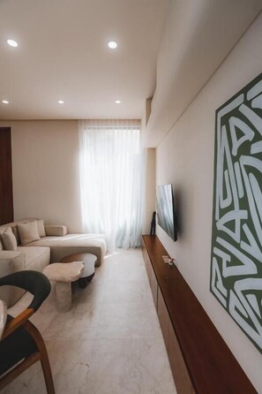 Uma sala de estar moderna com um sofá, uma mesa de centro e uma televisão fixada na parede.