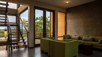 Sala moderna com escada, sofá e vista para o verde lá fora.