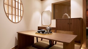 Um quarto em estilo japonês tradicional, com mesa de madeira, conjunto de chá e área de estar com tatames.