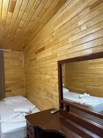 Quarto com painéis de madeira, duas camas, um espelho e um aparador de madeira.