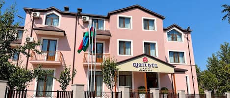 Edifício de hotel rosa com varandas e uma placa com a inscrição 'QIZILGÜL HOTEL'.