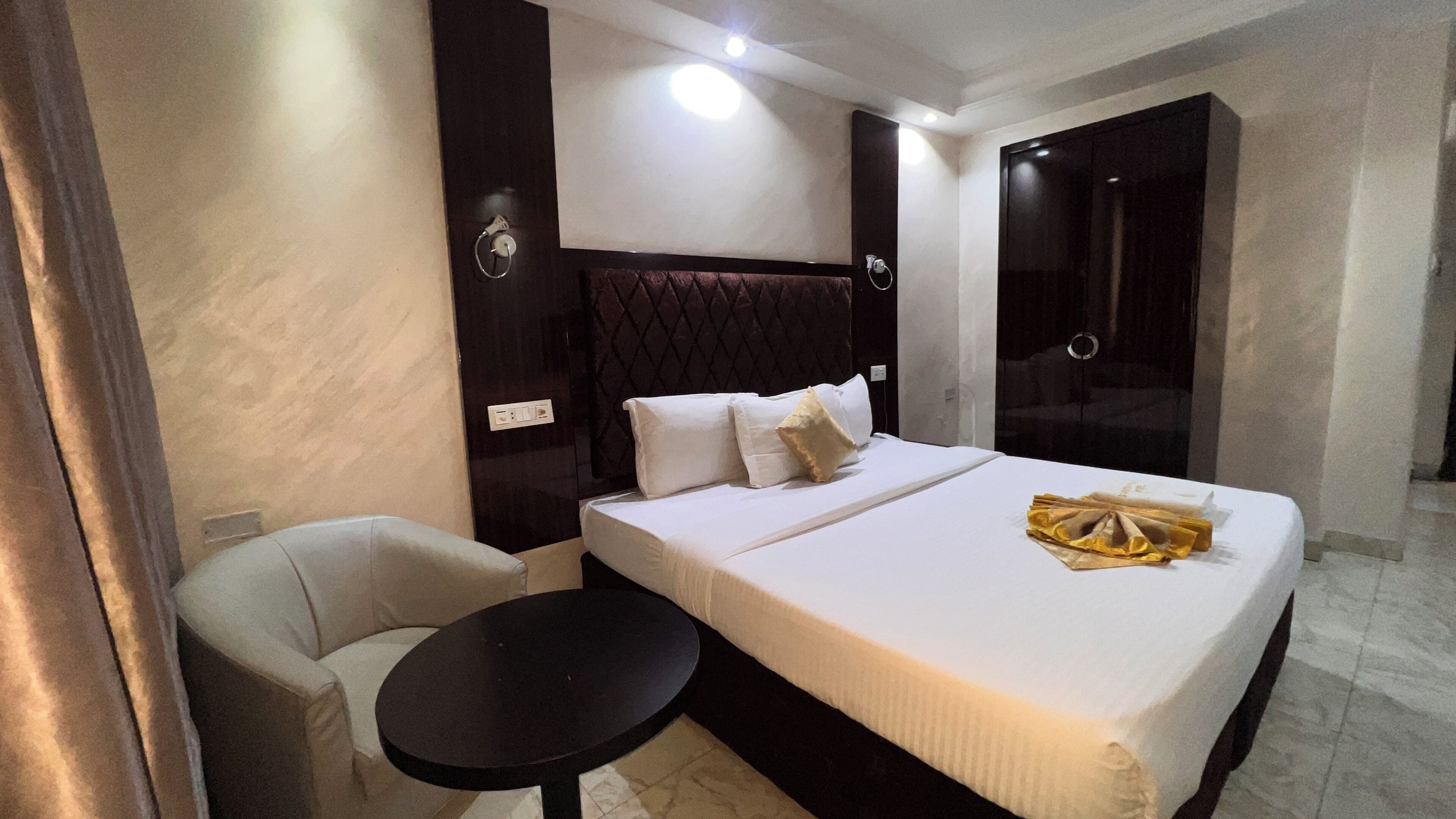 Quarto de hotel com cama, mesa de cabeceira e uma cadeira.