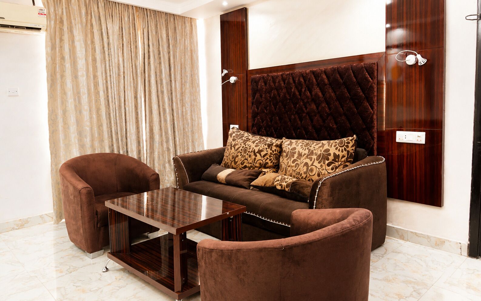 Uma sala de estar moderna com um sofá, duas poltronas e uma mesa de centro.