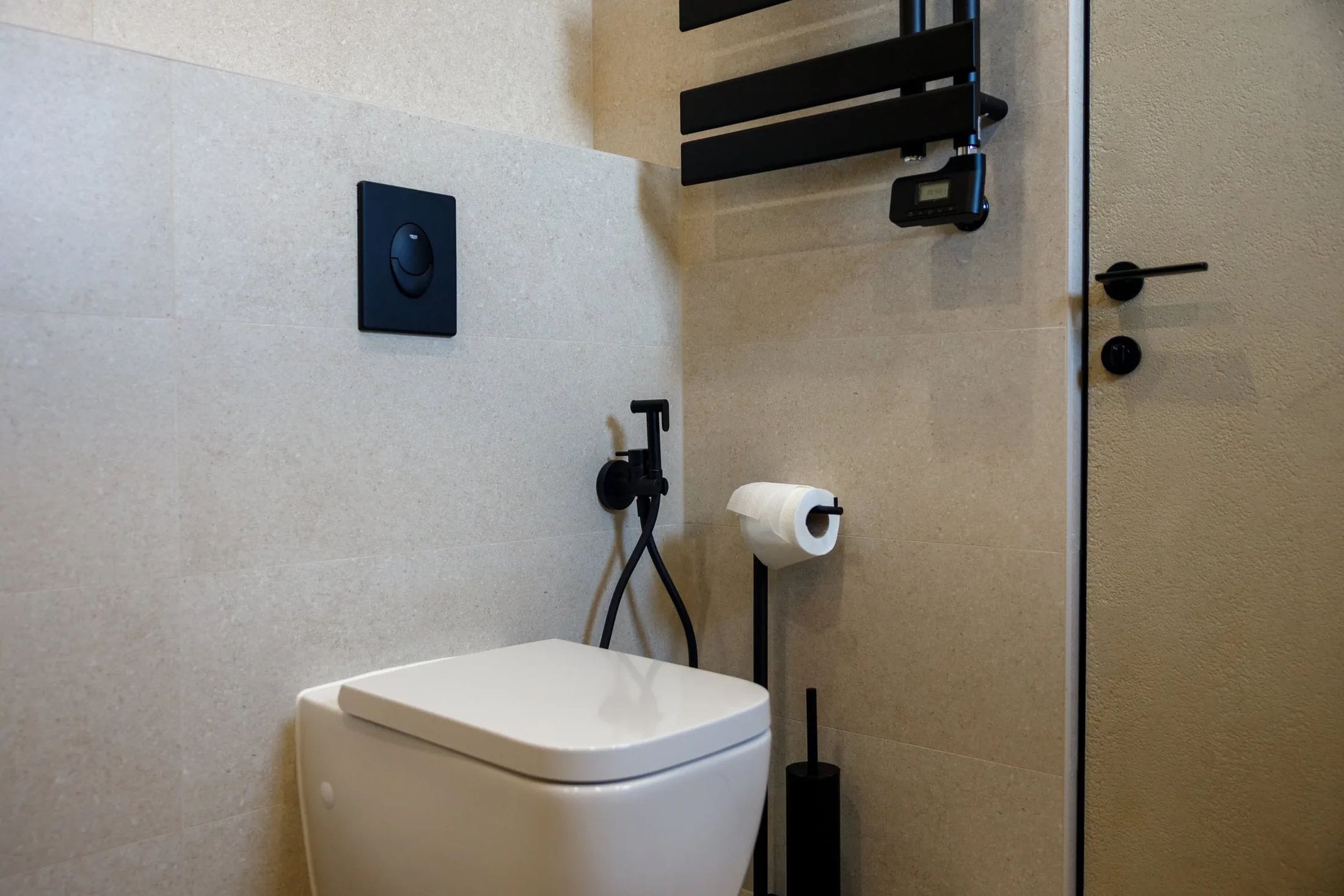 Uma casa de banho moderna com sanita, dispensador de papel e zona de duche.