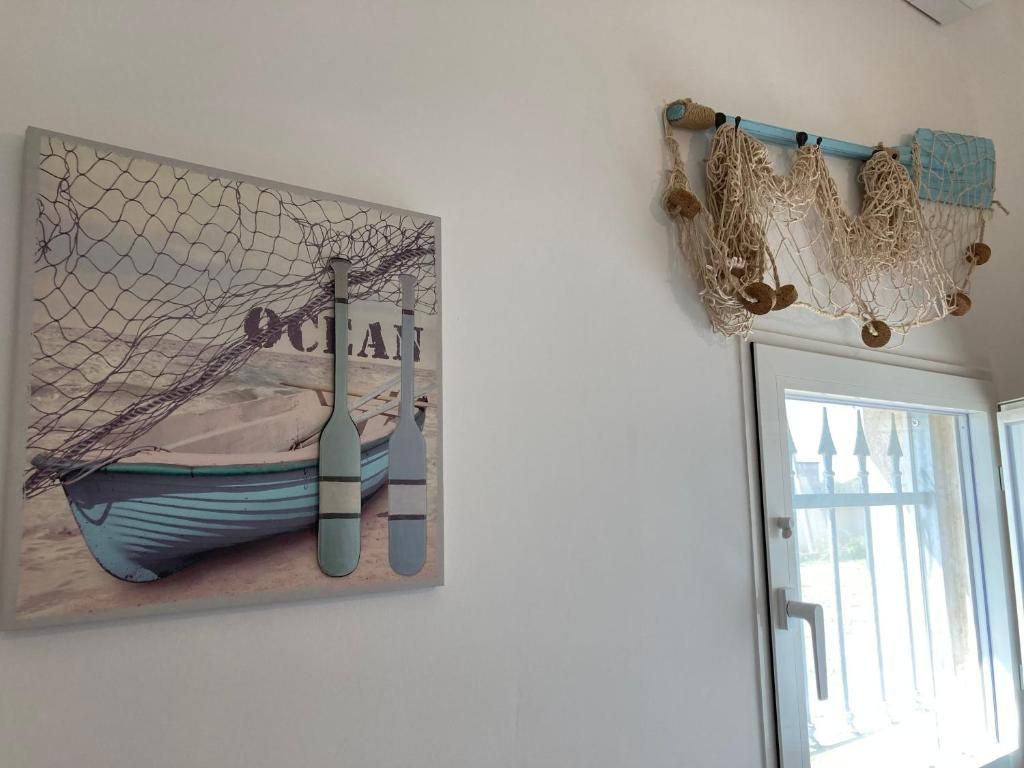 Paredes com pintura de tema náutico, uma porta e um pendente de macramé.