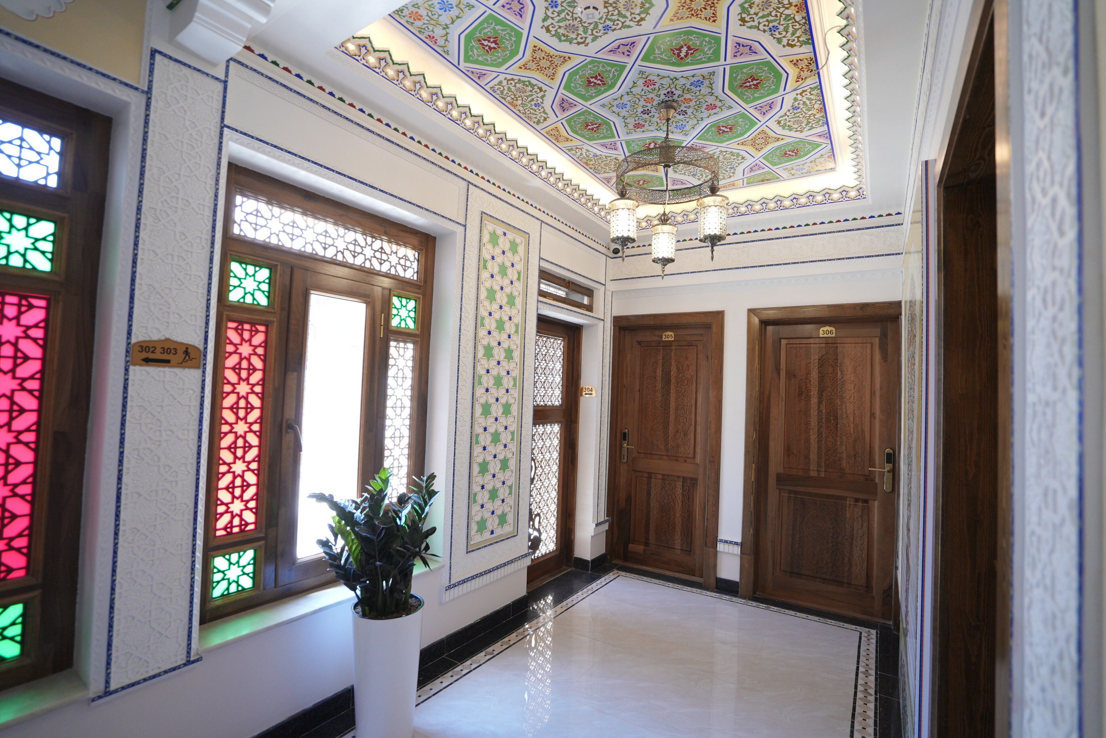 Corredor com teto decorado, portas de madeira e janelas com padrão.