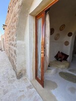Um quarto com porta de madeira, tapete pequeno e parede com detalhes circulares.