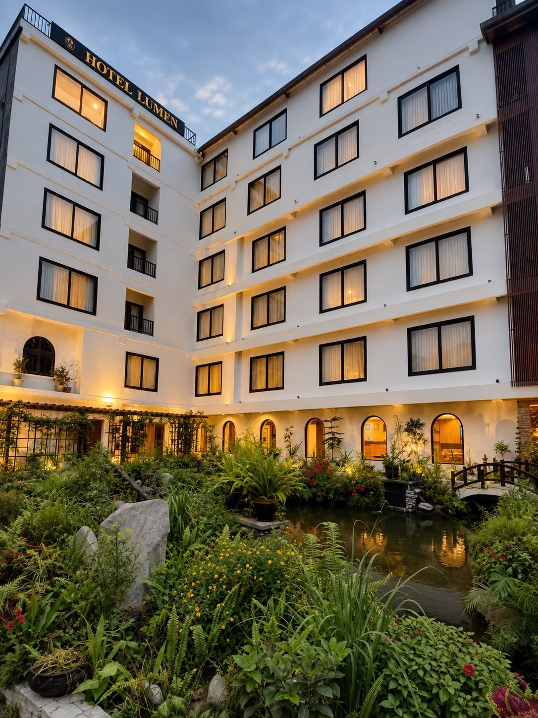 Hotel com vários andares e um pátio com fonte de água e vegetação exuberante.