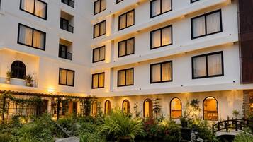 Hotel com vários andares e um pátio com fonte de água e vegetação exuberante.