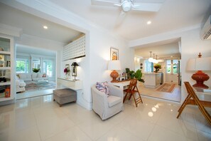 Uma sala de estar espaçosa com um sofá branco, uma mesa de centro e uma área de jantar com mesa e cadeiras.