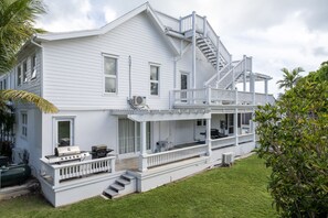 Uma casa de dois andares com varanda frontal, escada e piscina.