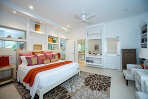 Quarto moderno com cama grande, mesas de cabeceira, ventoinha no teto e estantes embutidas.
